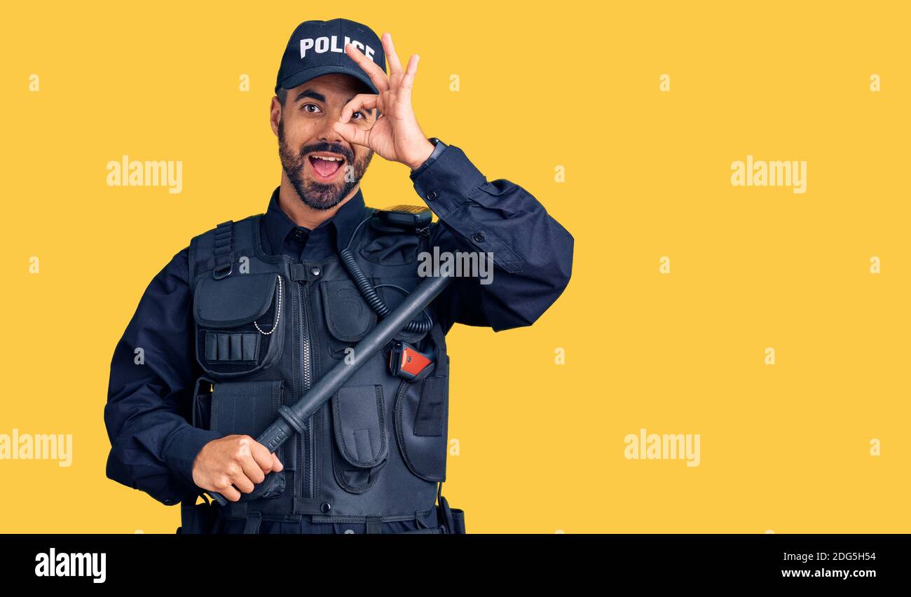 Young hispanic man wearing police uniform holding baton smiling happy ...