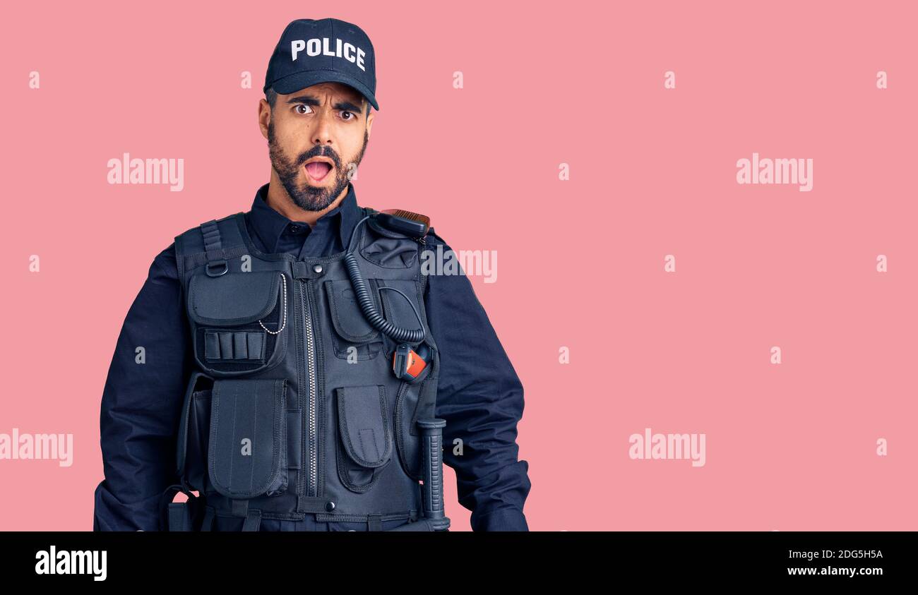 Young hispanic man wearing police uniform in shock face, looking ...