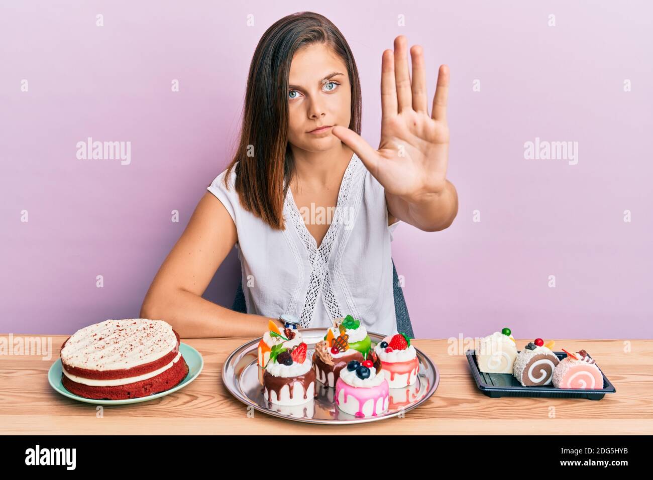 Young caucasian woman eating pastries with open hand doing stop sign ...