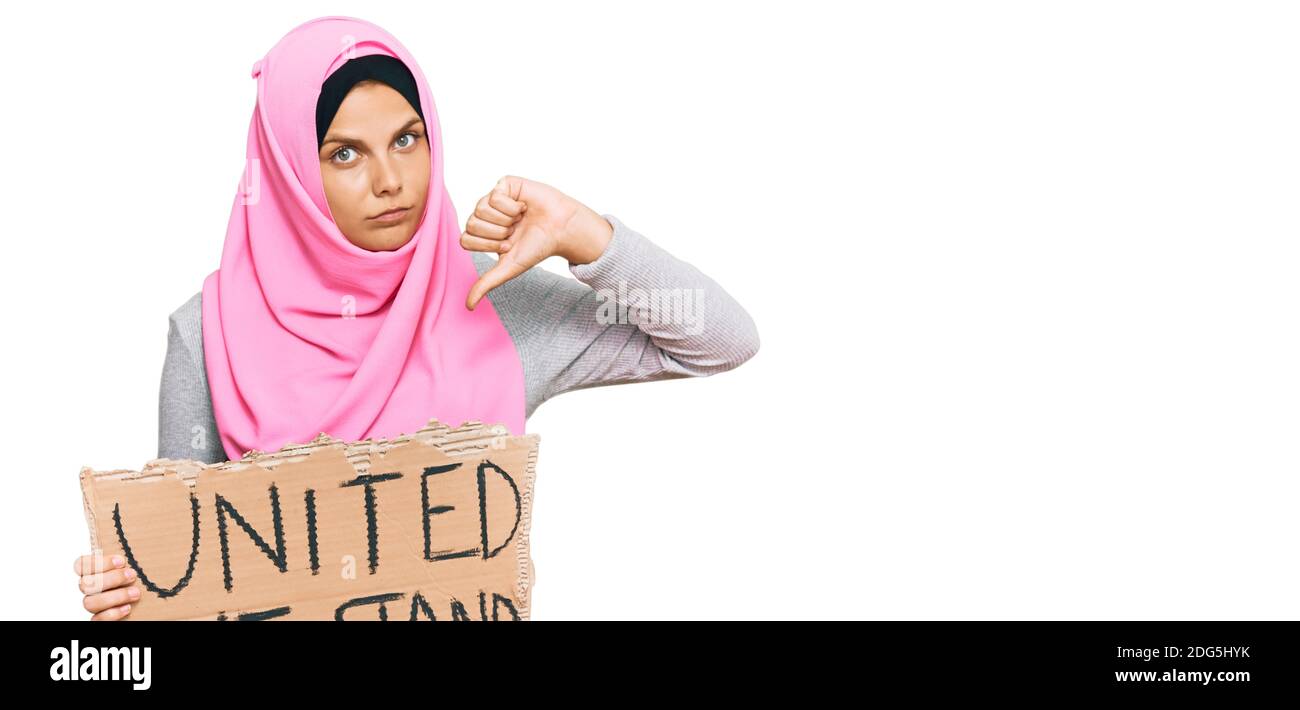 Young caucasian woman holding united we stand banner with angry face ...