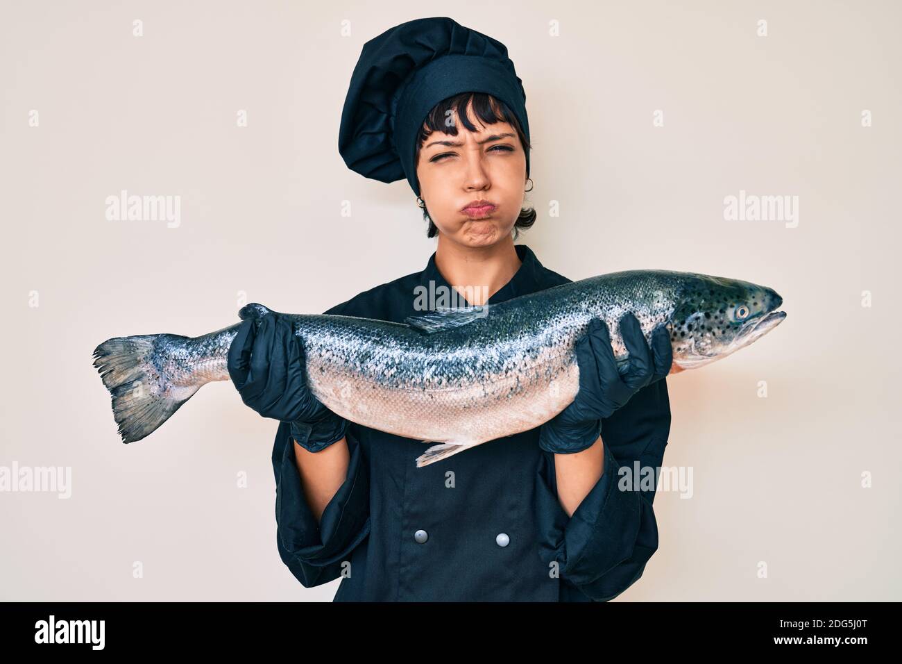 Beautiful brunettte woman professional chef holding fresh salmon fish ...