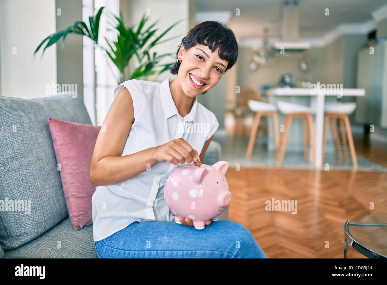 Young brunette woman smiling happy putting money savings inside of ...