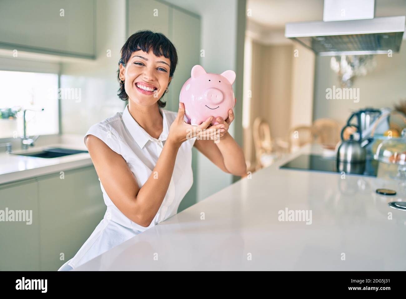 Young brunette woman smiling happy showing proud piggy bank with ...