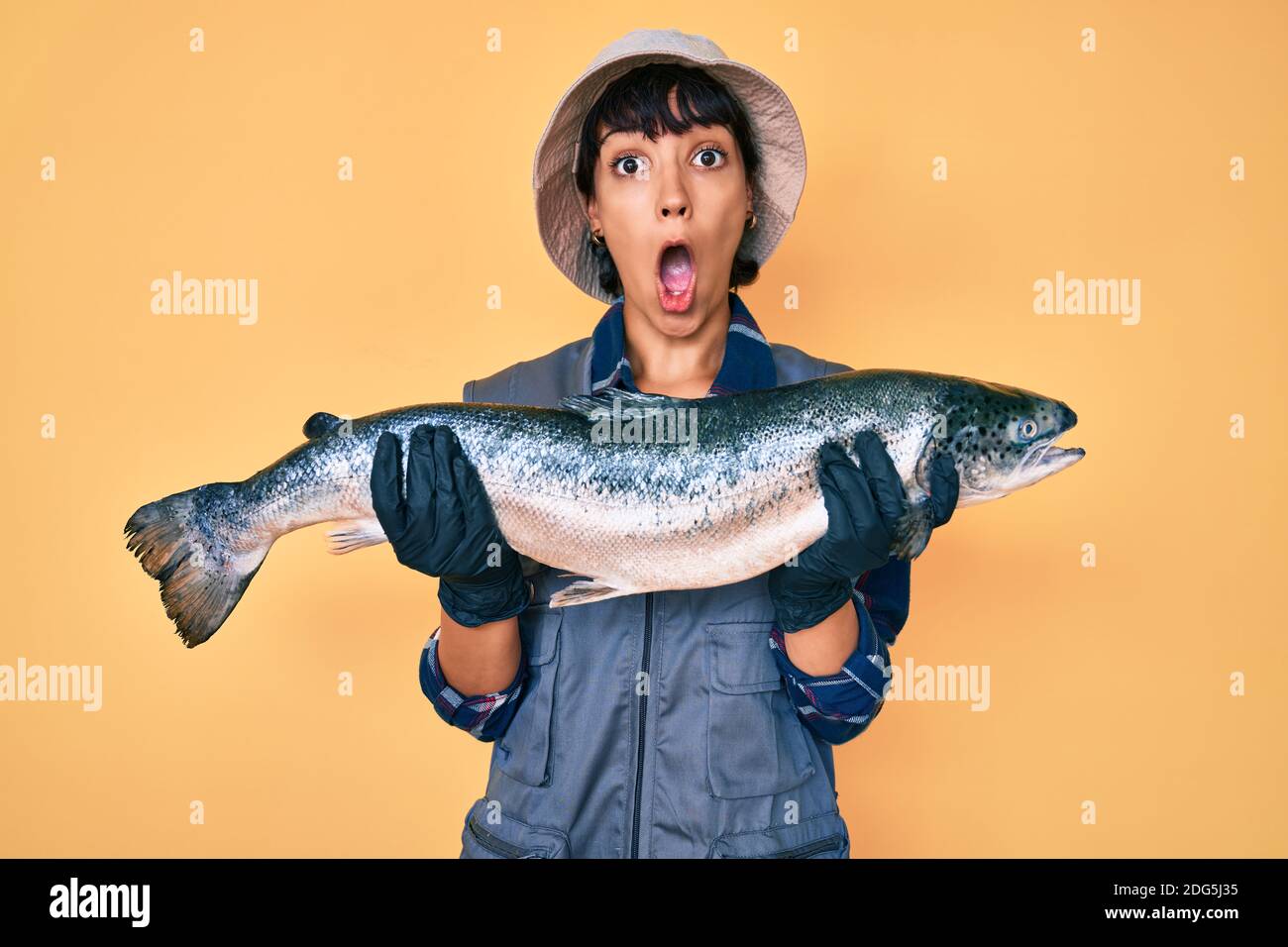 Beautiful brunettte fisher woman showing raw salmon afraid and shocked ...
