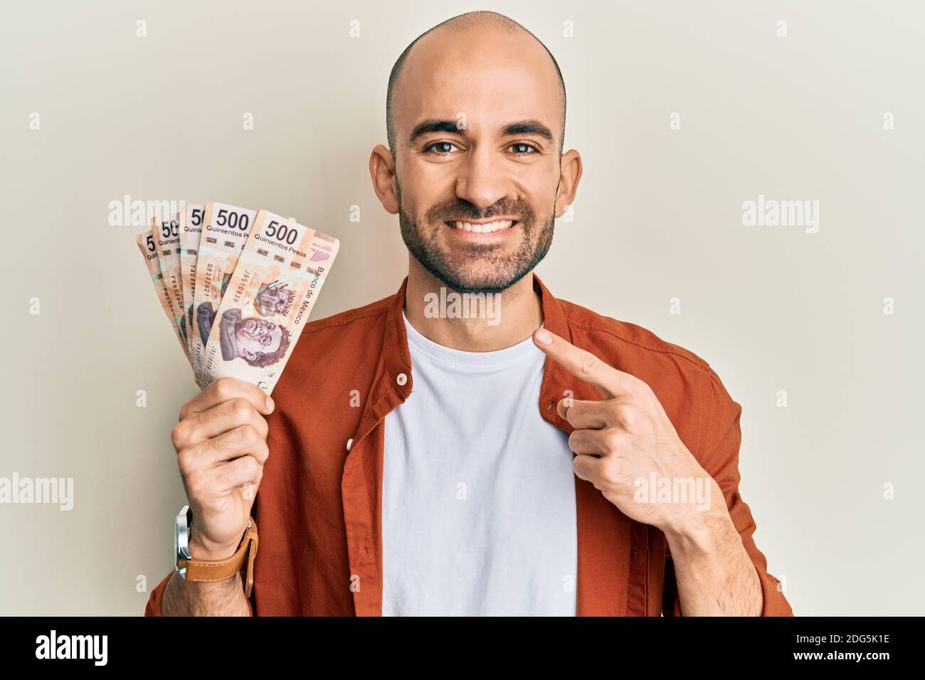 Young hispanic man holding 500 mexican pesos banknotes smiling happy ...