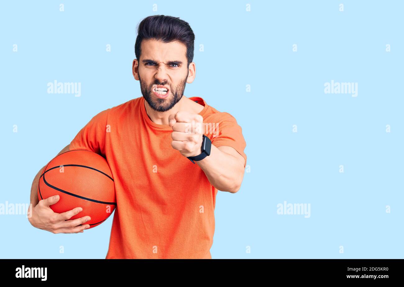 Young handsome man with beard hoilding basketball ball annoyed and ...