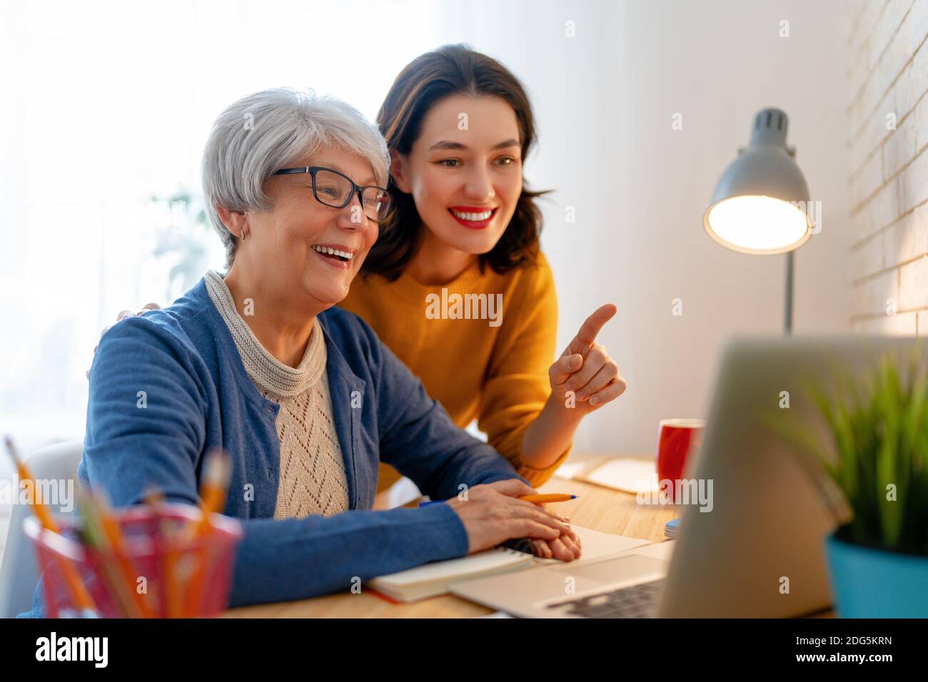 Young and senior women are using laptop pc. Daughter is helping mother ...