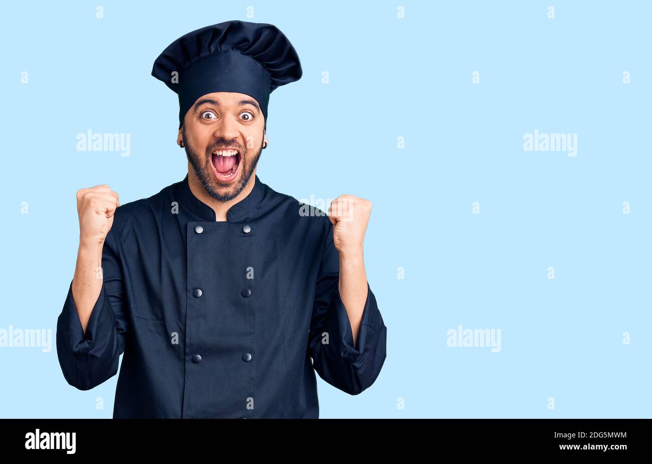 Young hispanic man wearing cooker uniform celebrating surprised and ...