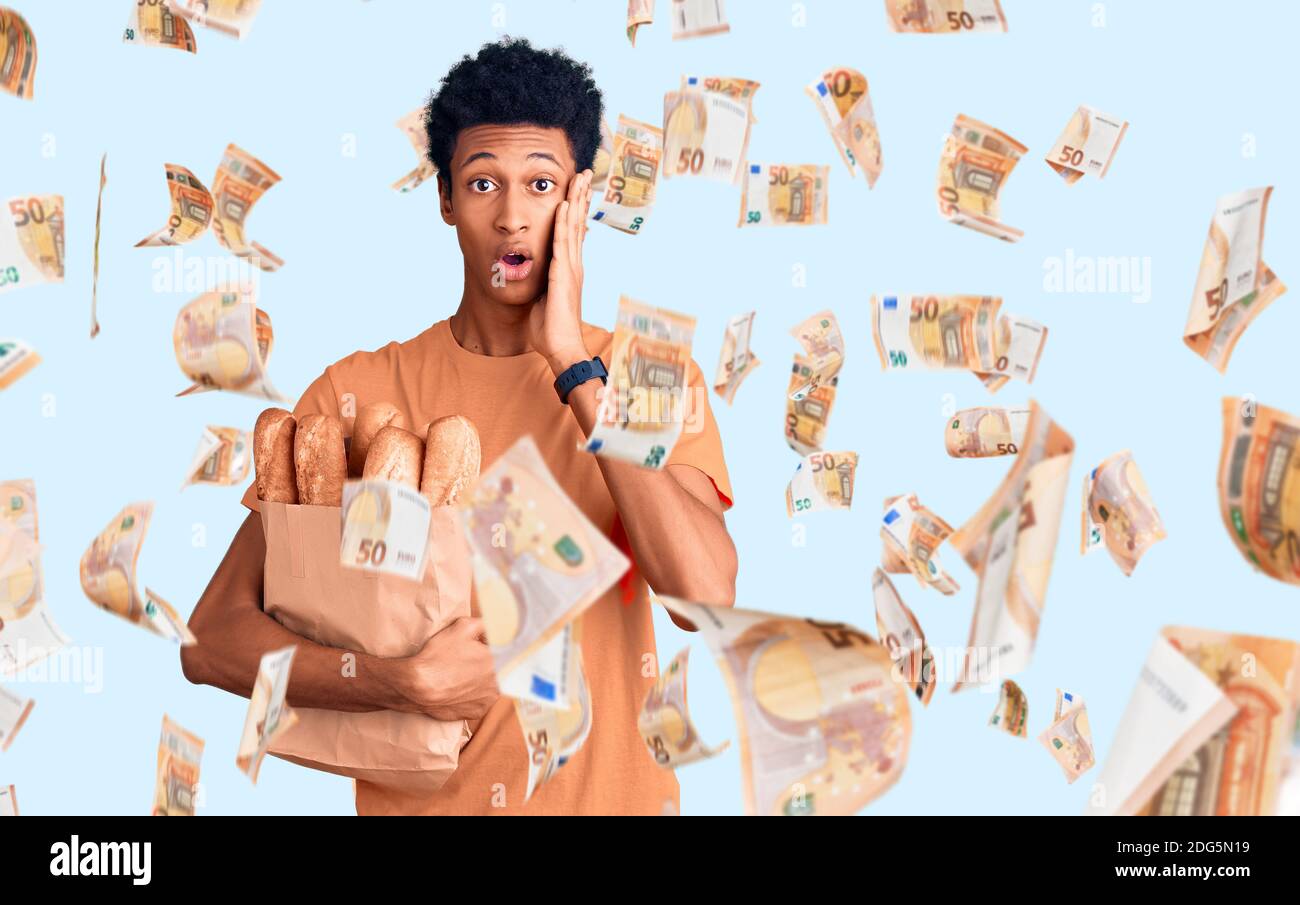 Young african american man holding paper bag with bread afraid and ...