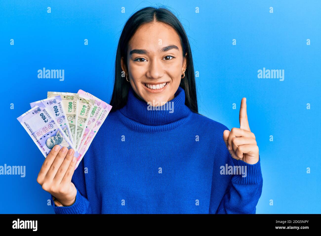 Young asian woman holding indian rupee banknotes smiling with an idea ...
