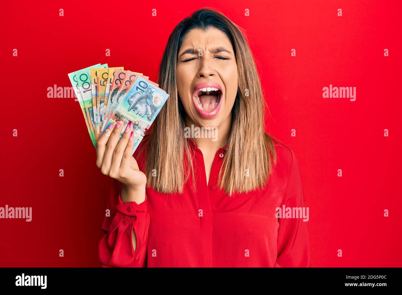 Beautiful brunette woman holding australian dollars angry and mad ...