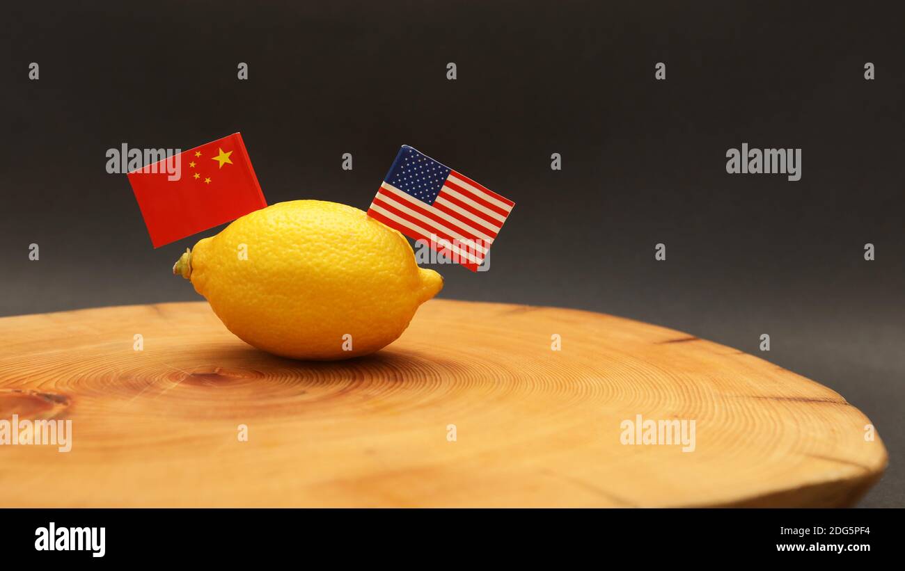 US American and Chinese flags poking out of a lemon on a chopping block ...
