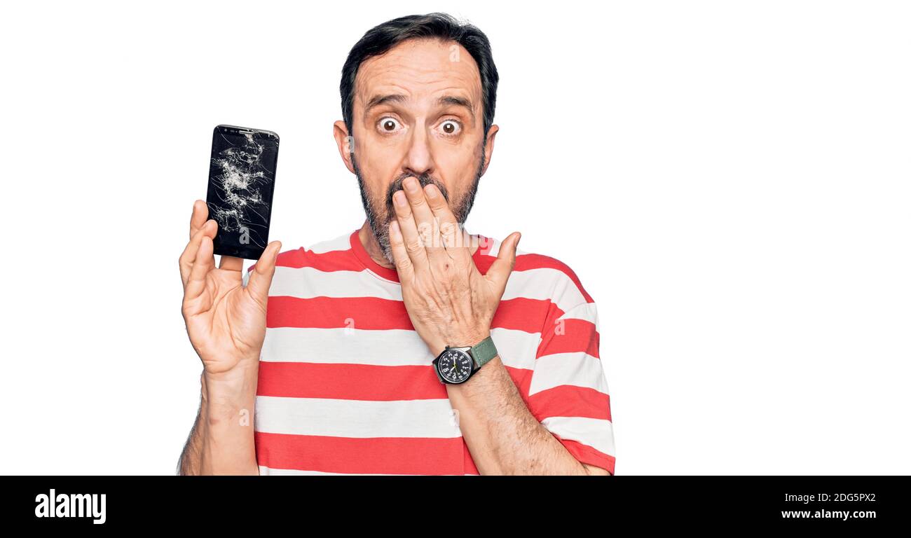 Middle age man holding broken smartphone showing cracked screen over ...