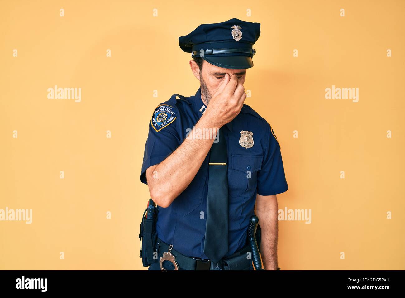 Middle age hispanic man wearing police uniform tired rubbing nose and ...