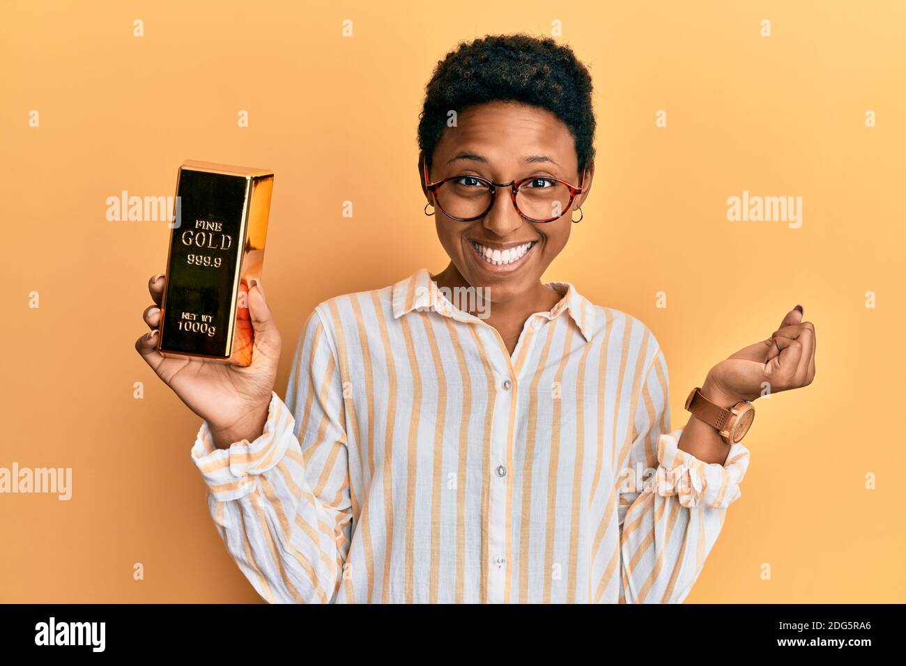 Young african american girl holding gold ingot screaming proud ...