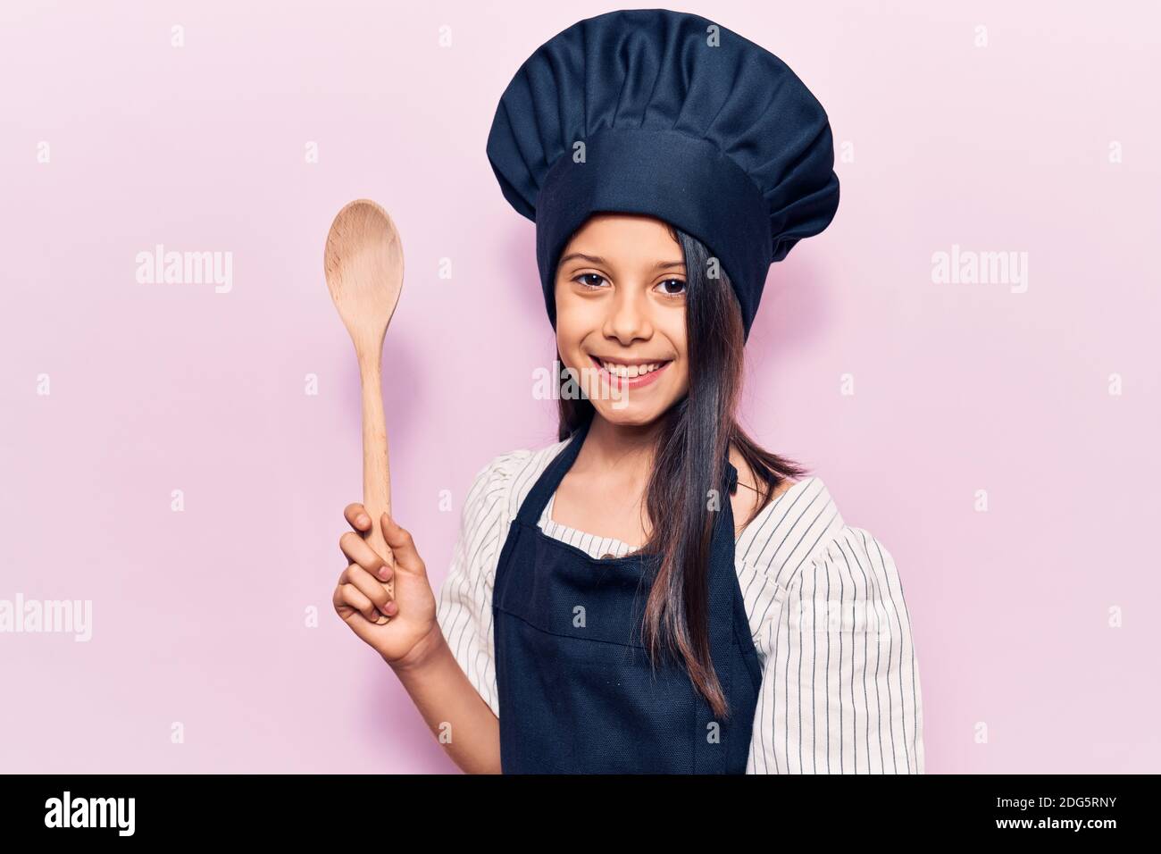 Beautiful child girl wearing cooker uniform looking positive and happy ...