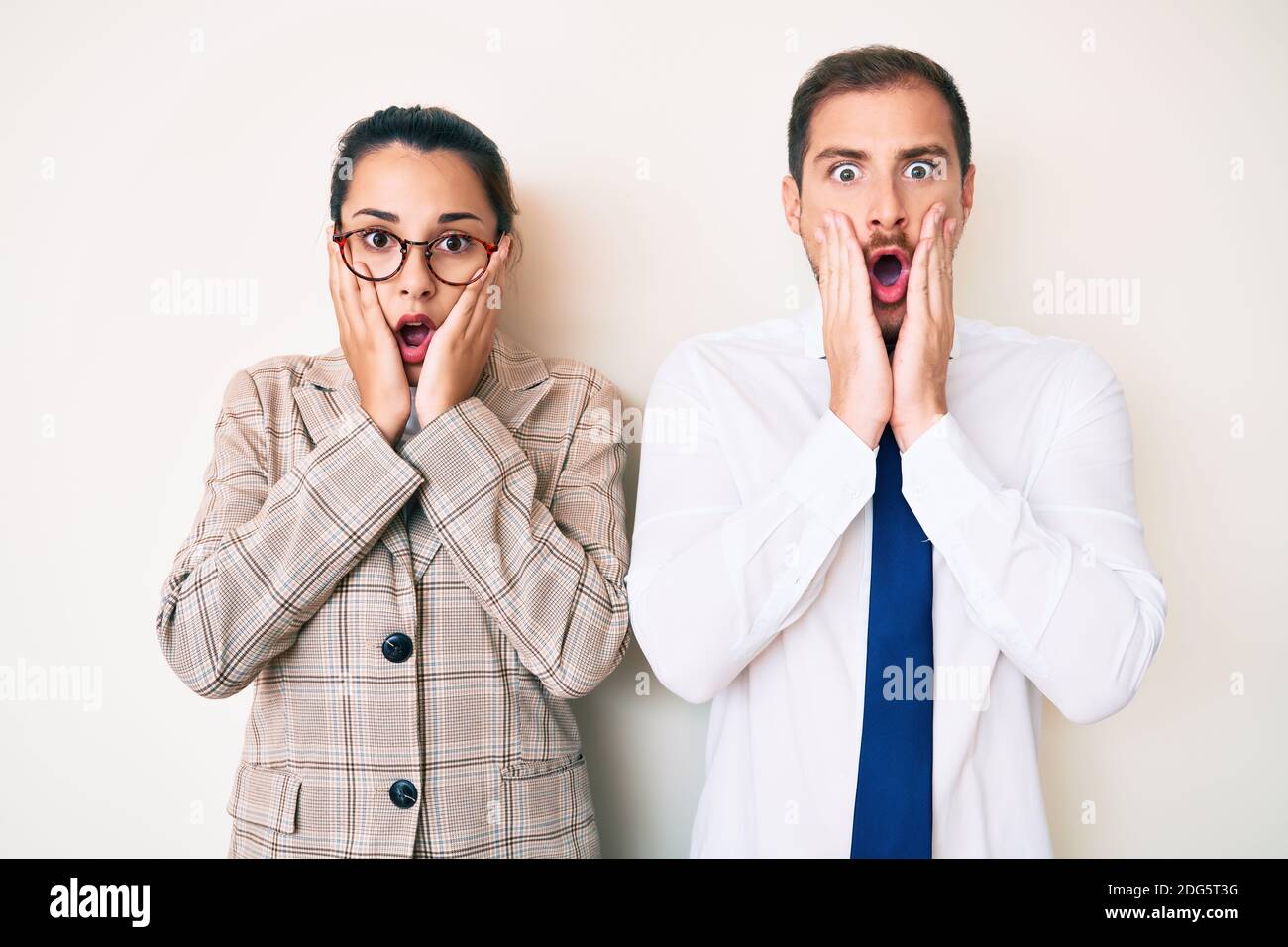 Beautiful couple wearing business clothes afraid and shocked, surprise ...