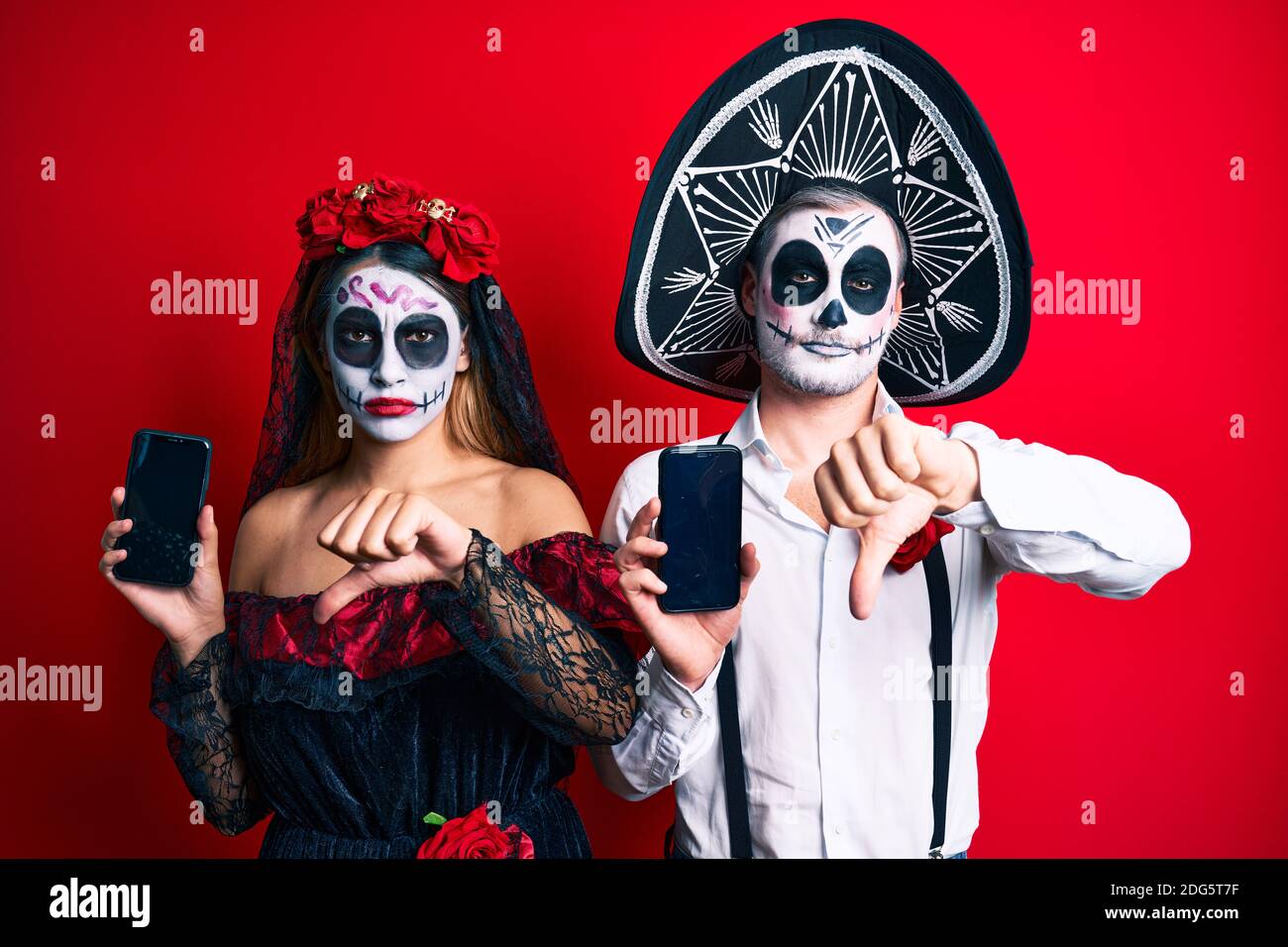 Couple wearing day of the dead costume holding smartphone showing ...