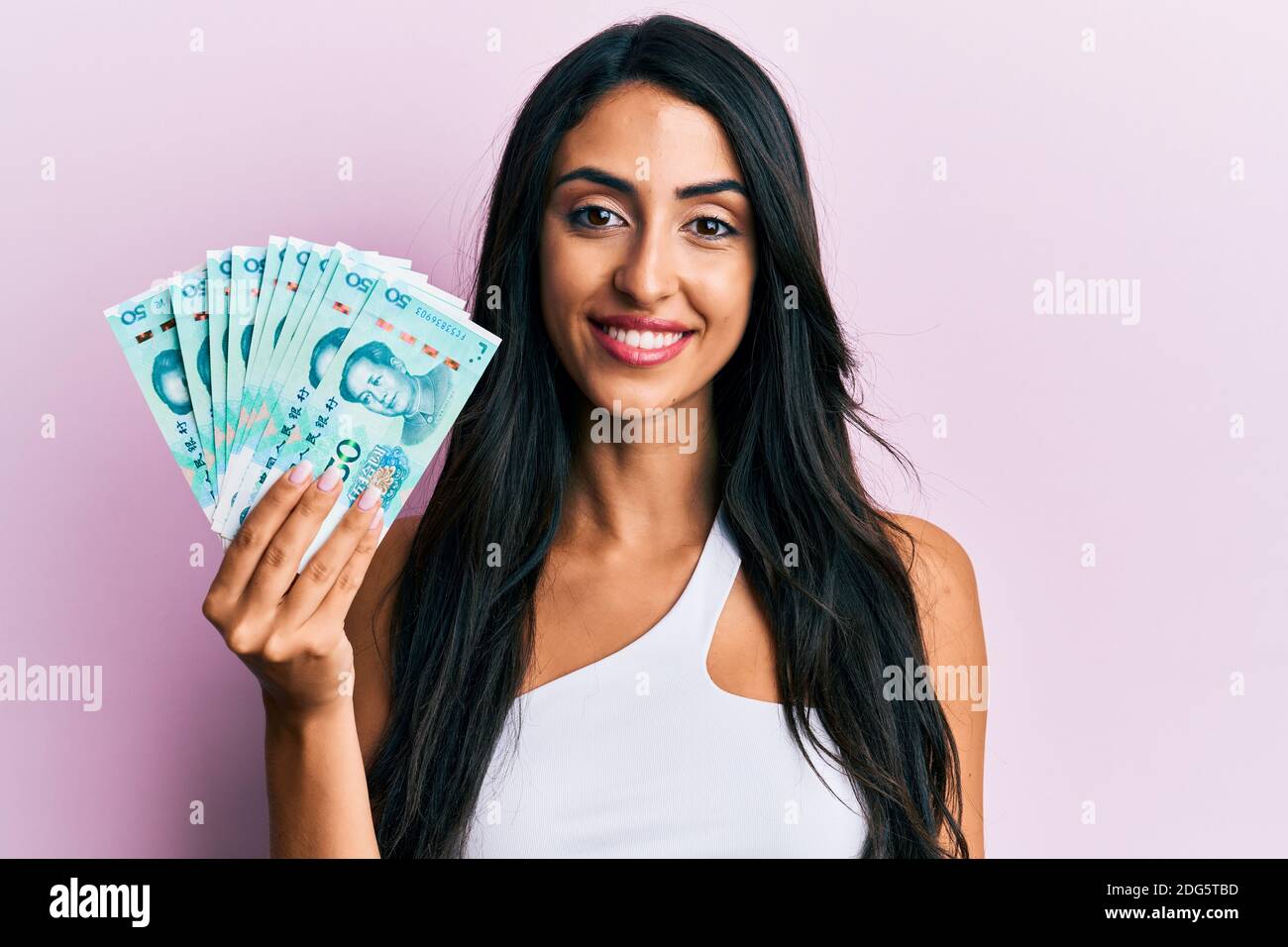 Beautiful hispanic woman holding yuan chinese banknotes looking ...