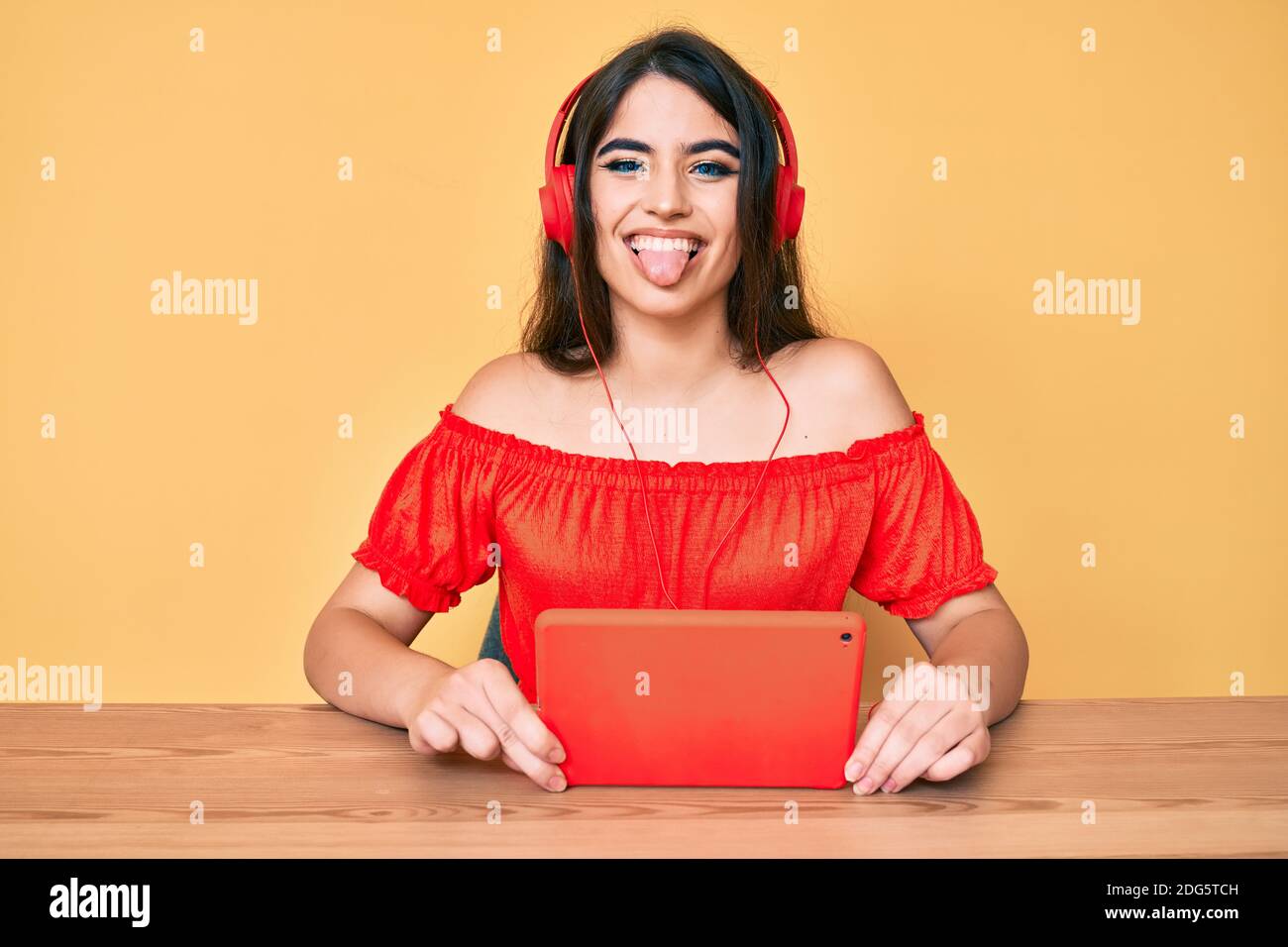 Brunette teenager girl using touchpad wearing headphones sticking ...