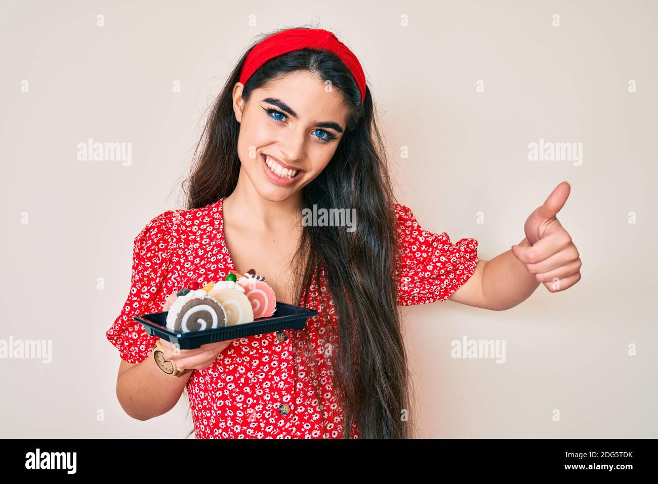 Brunette teenager girl holding cake sweets smiling happy and positive ...