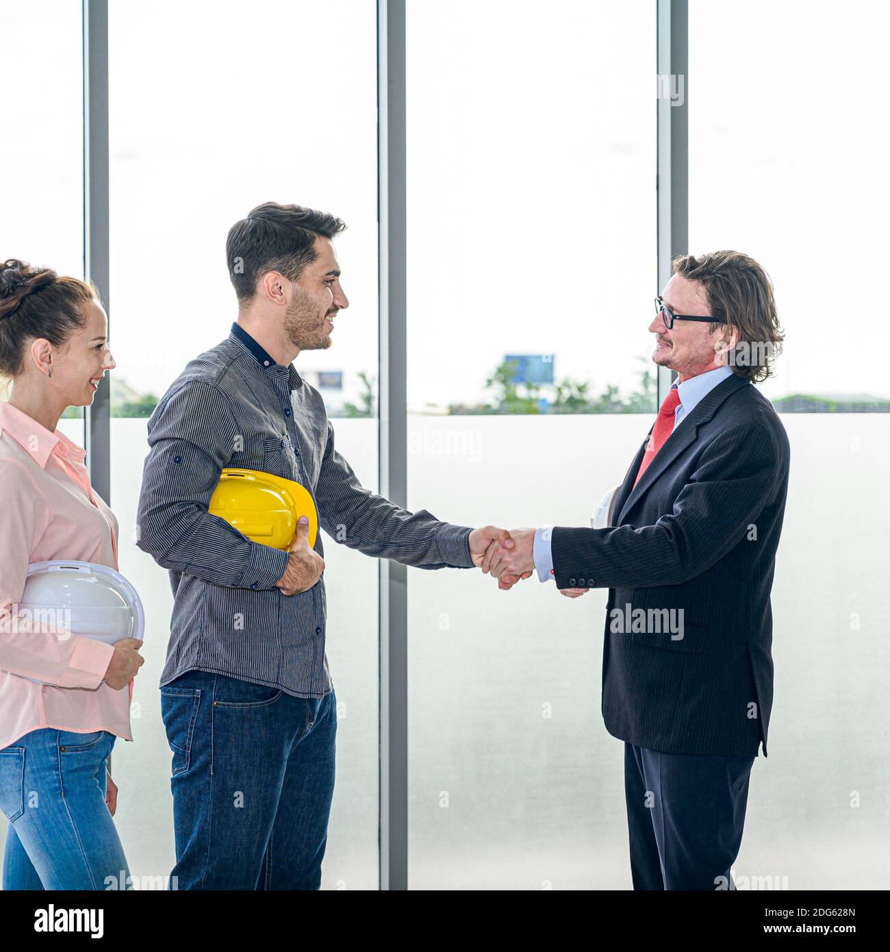 Two Caucasian architect or engineer holding helmet and smiling ...