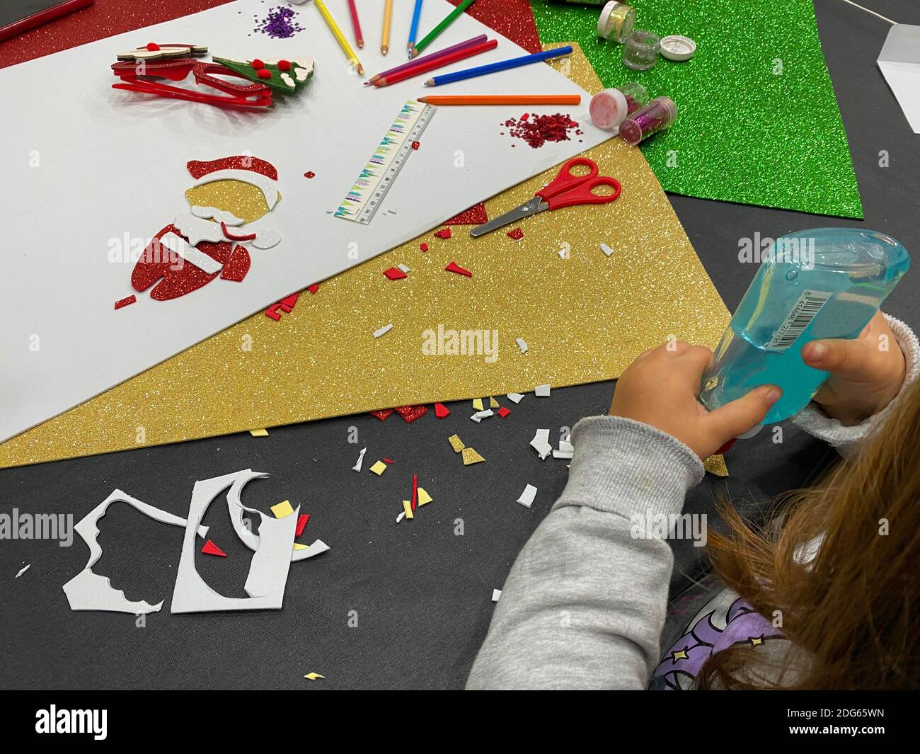 Close-up of a girl's hands using the glue to make a Christmas craft ...
