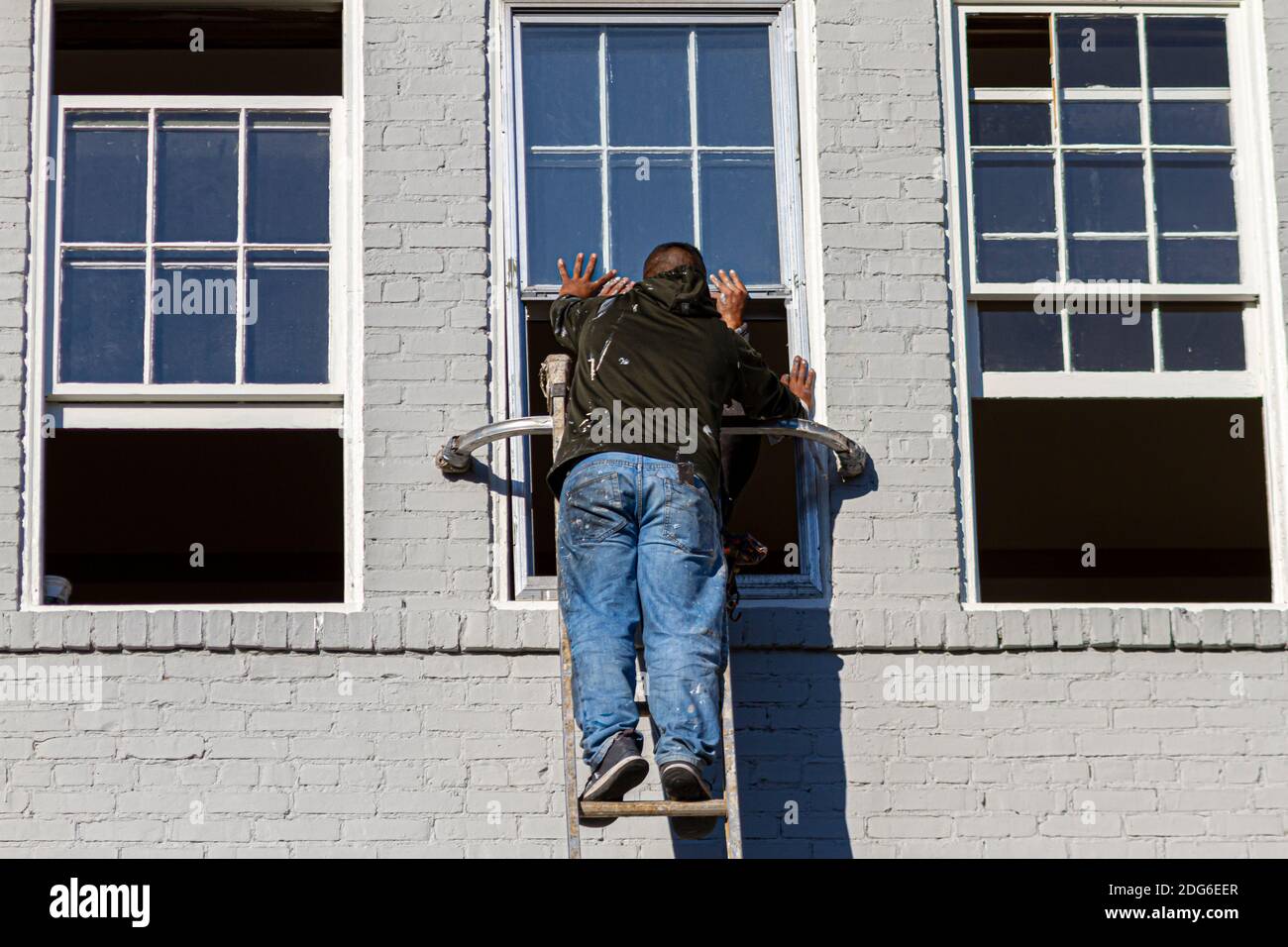 A hispanic repair man wearing jeans and sneakers is on top of a ...
