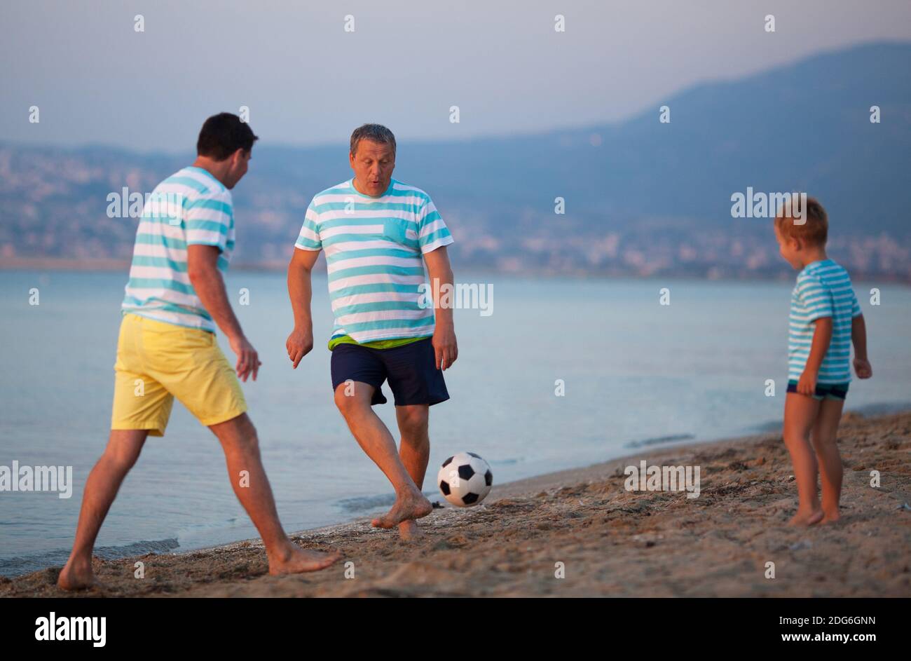 Family team of three playing football at the seaside Stock Photo - Alamy
