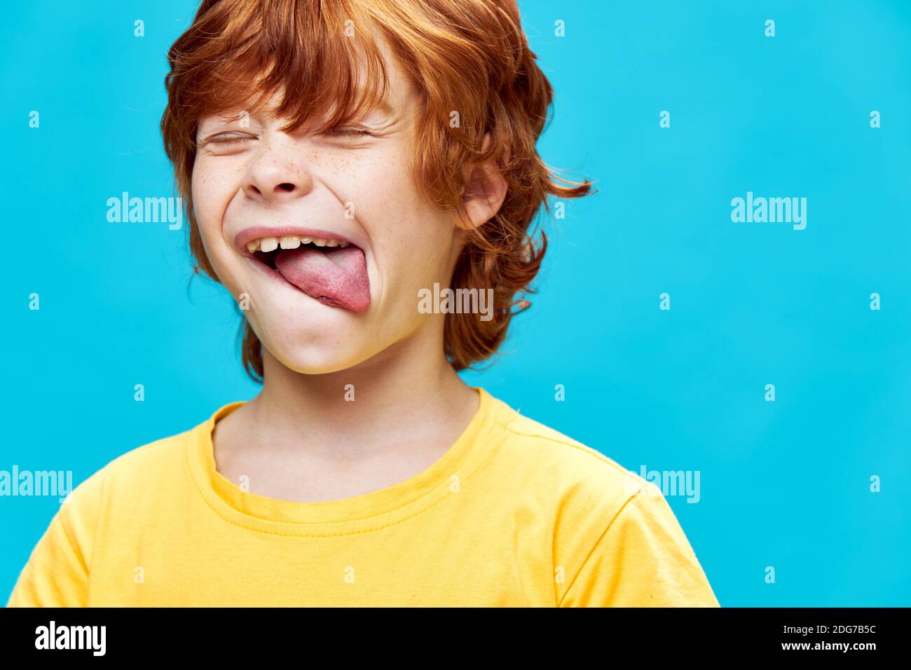 redhead boy grimacing showing tongue eyes closed yellow t-shirt ...