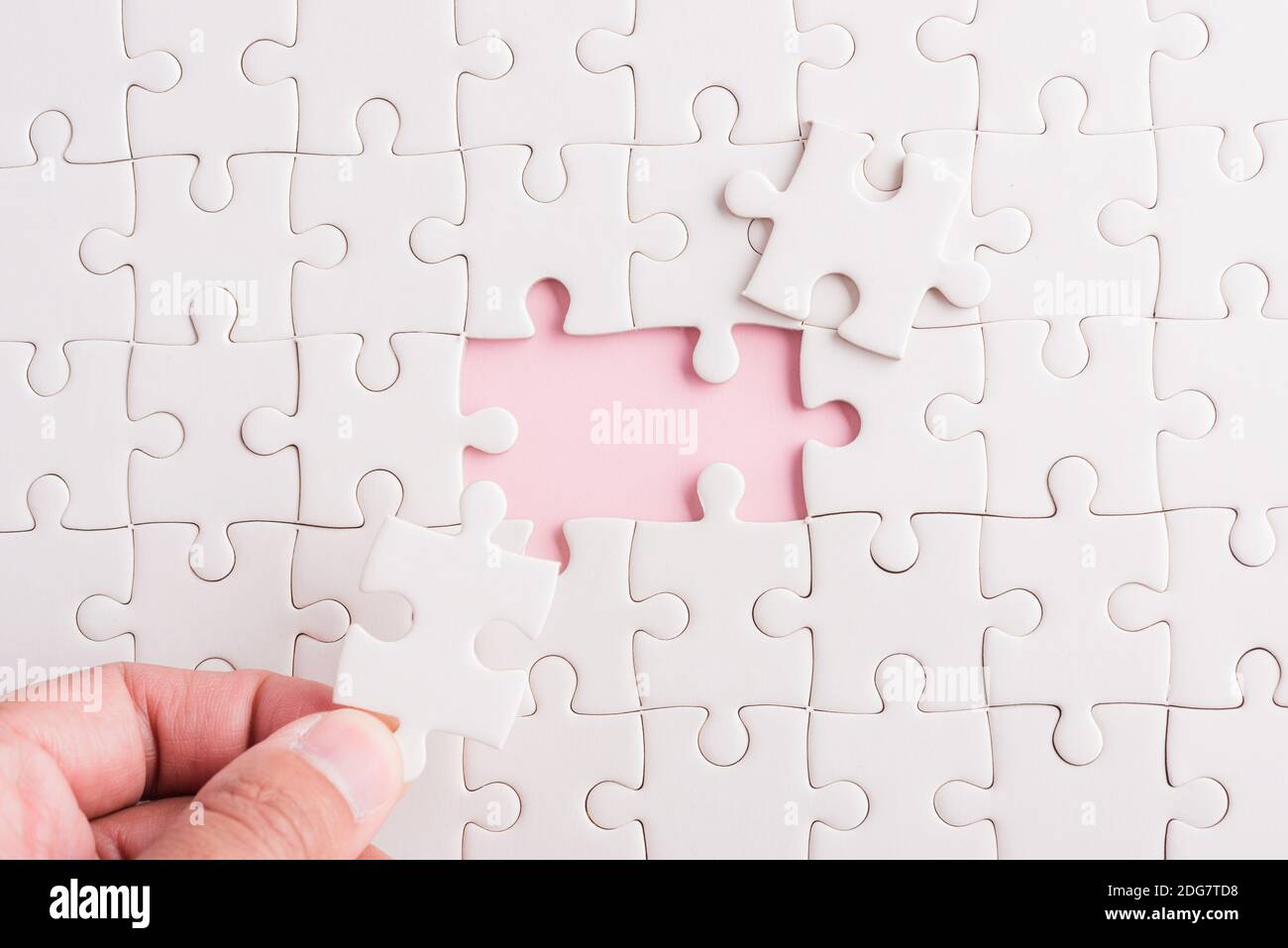 Top view flat lay of hand-holding last piece white paper jigsaw puzzle ...