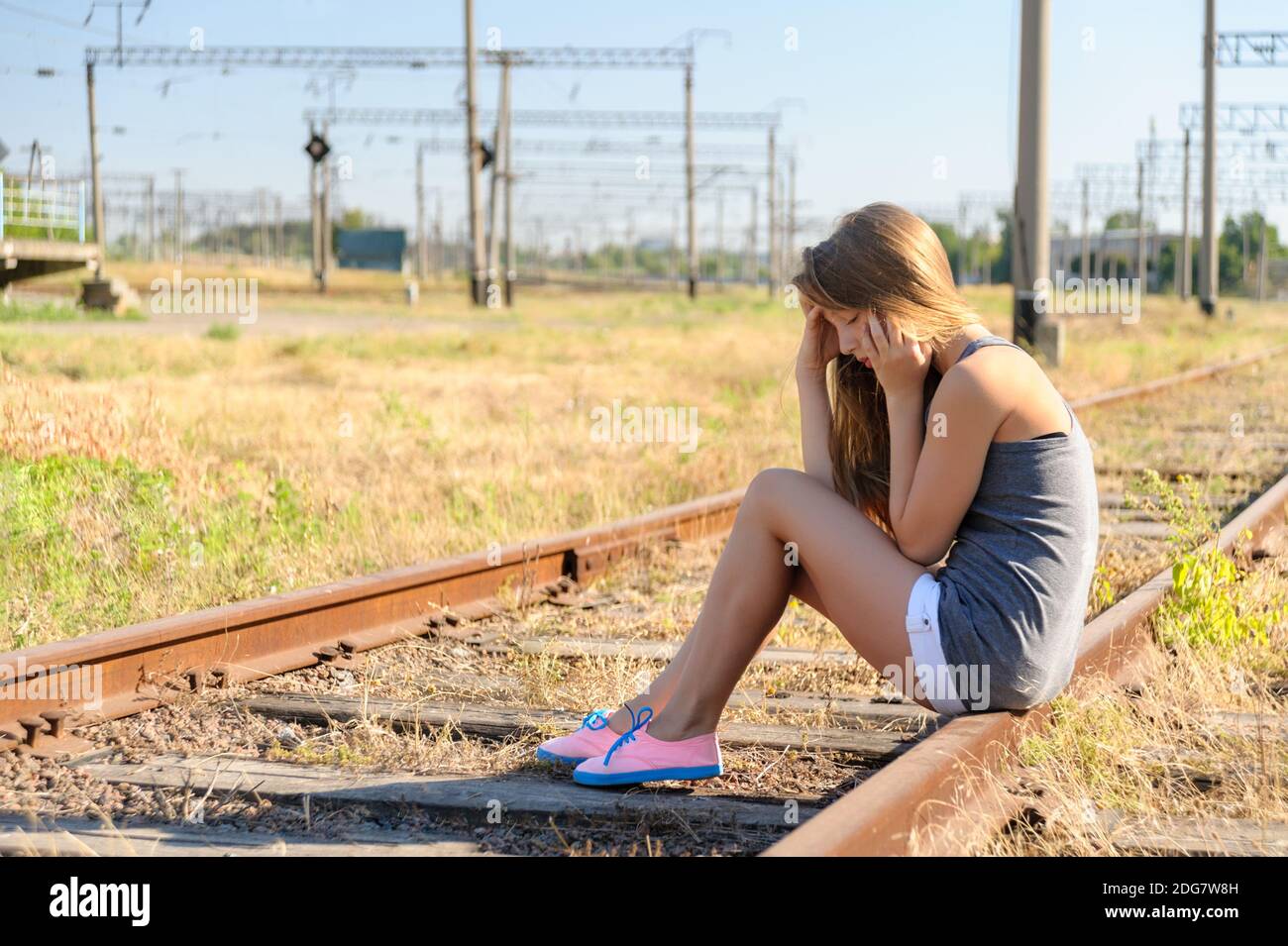 Upset teenager girl sitting on rail track in countryside Stock Photo ...