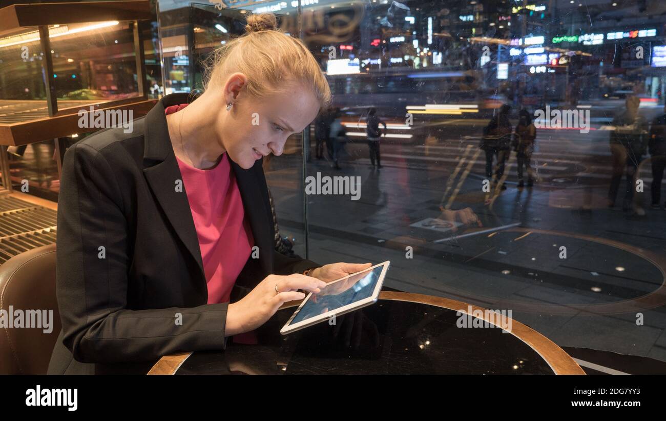 Woman using pad in cafe by window with city view Stock Photo - Alamy