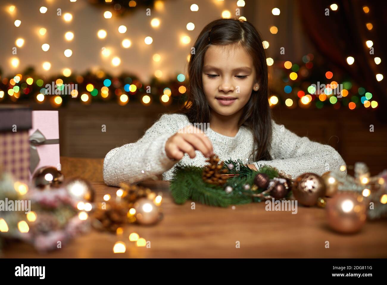 happy cute little child girl makes a handmade Christmas wreath at home ...