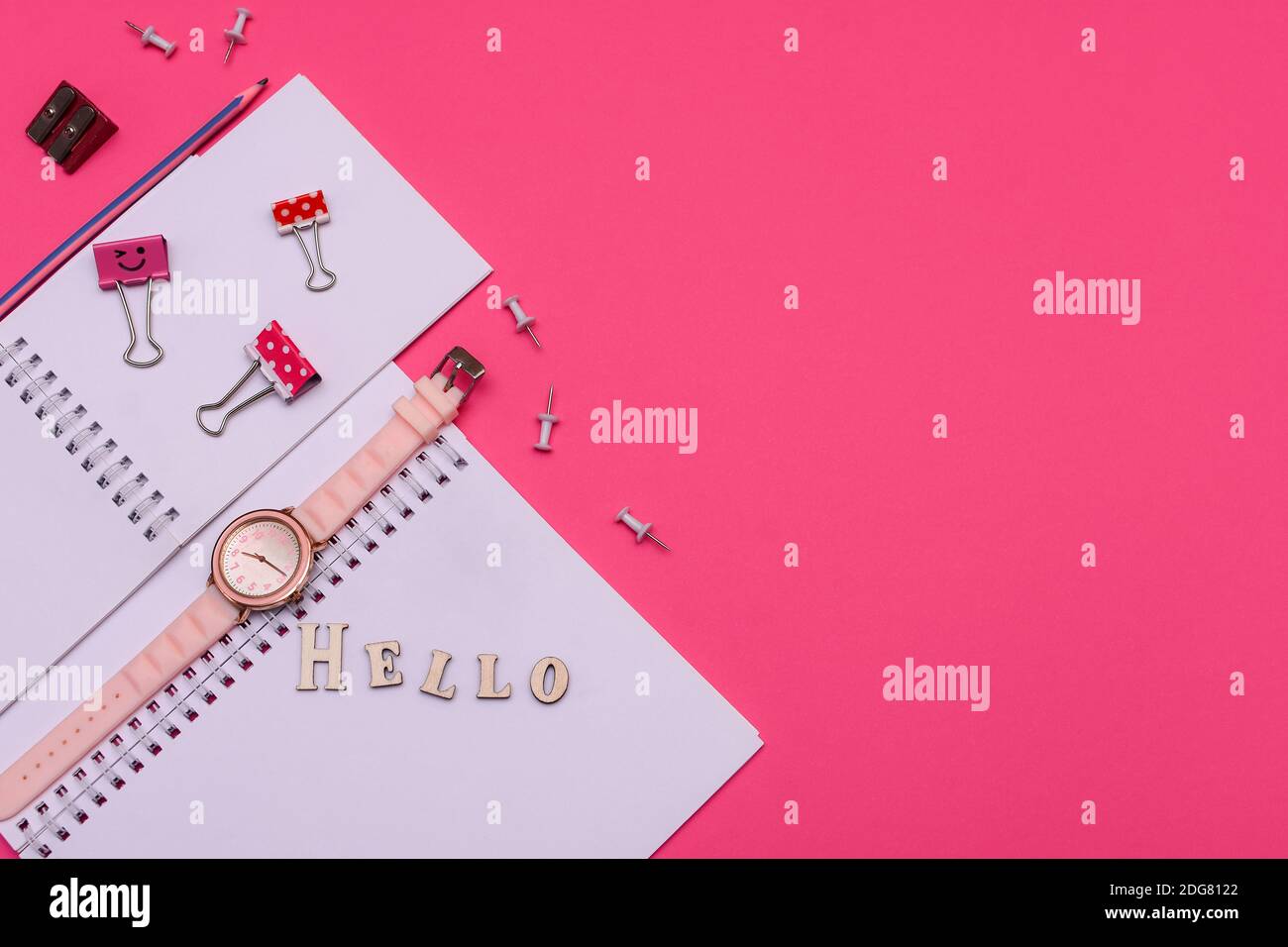 Pink work desk with blank notebook and office supplies. Top view with ...