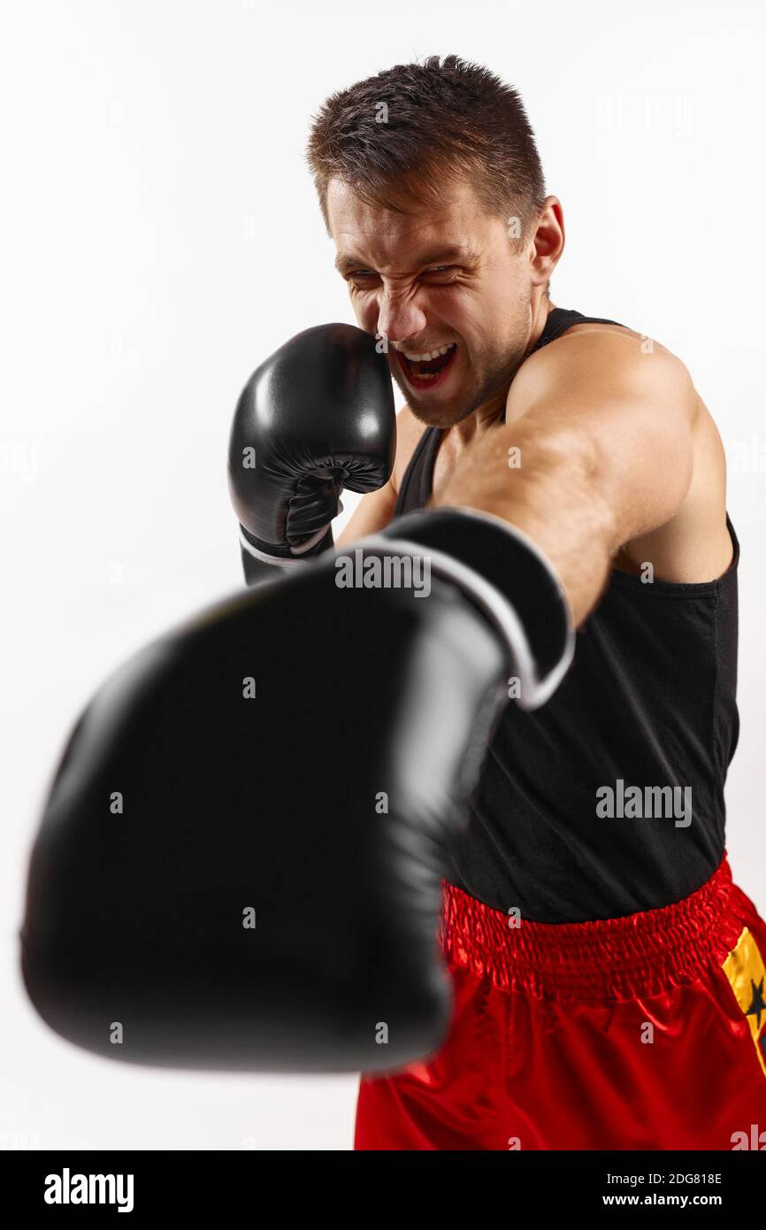 sporty man in black boxing gloves hitting at camera isolated on white ...