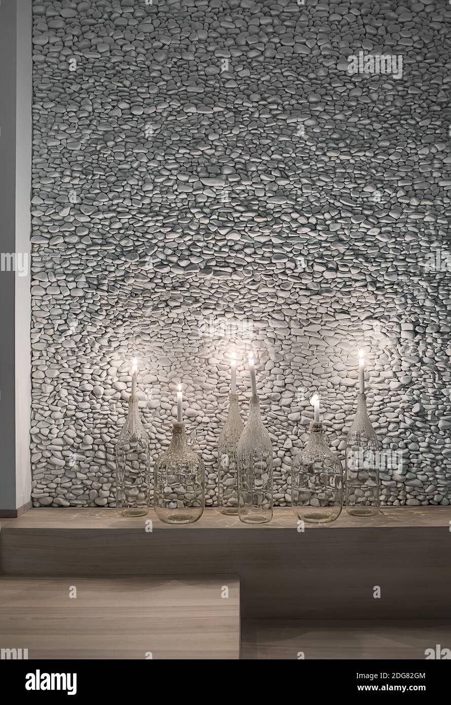 Stylish candlesticks on pebble wall background Stock Photo - Alamy