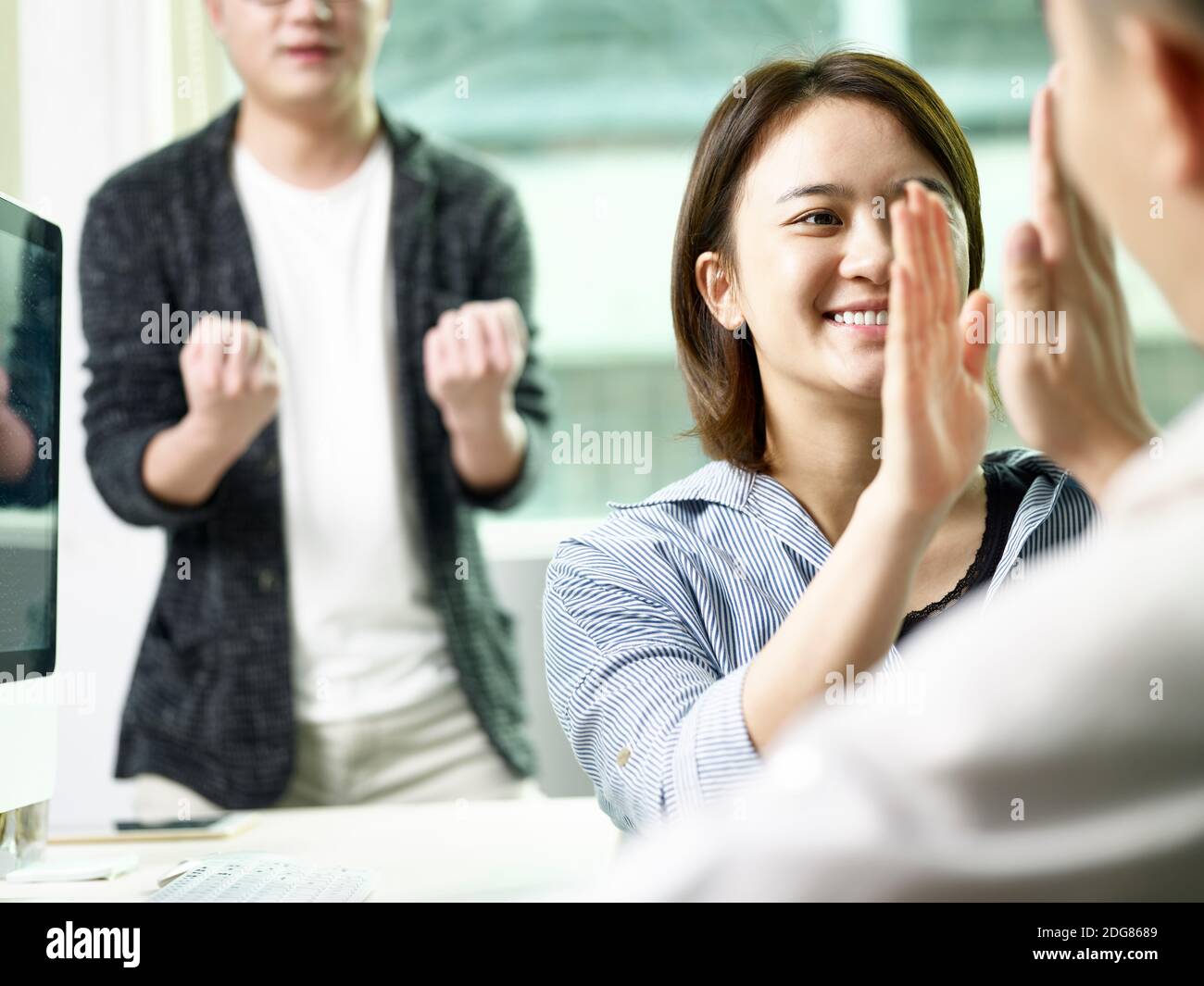 team of three asian business people giving hi-five celebrating ...