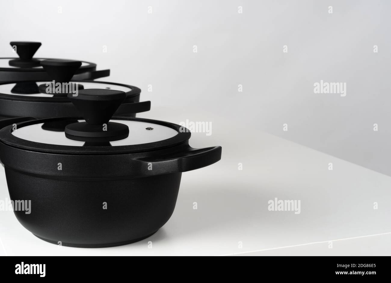 Black cooking pots on grey background front view Stock Photo - Alamy