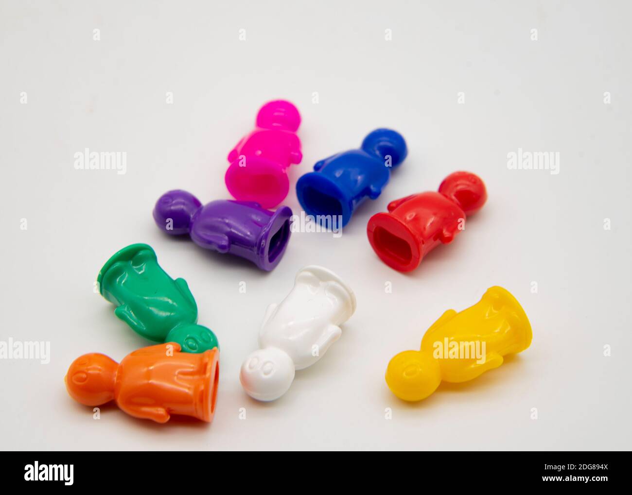 Board game colorful plastic figurines lie in a pile on a light ...