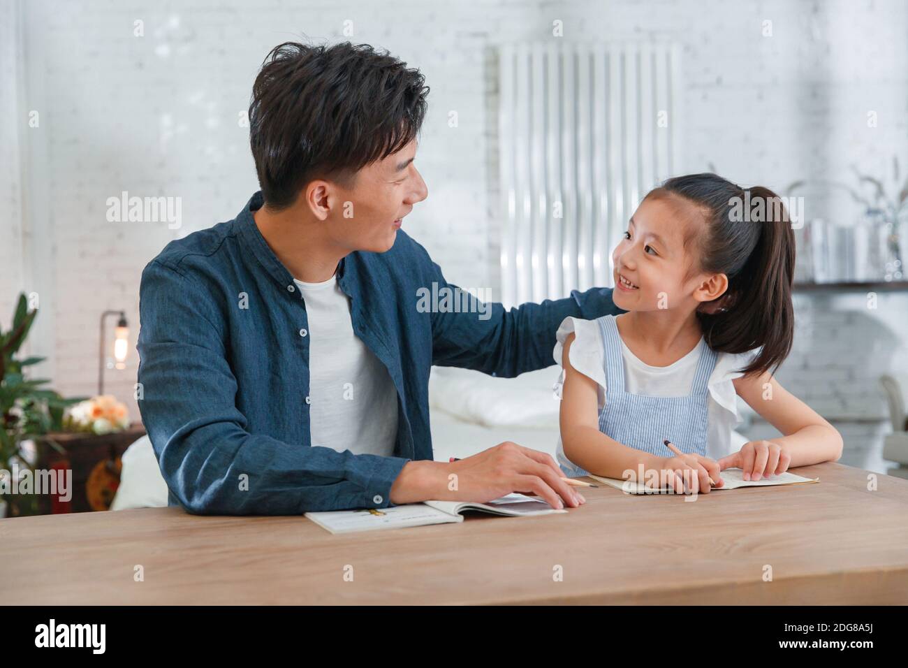 The young man to coaching daughter doing his homework Stock Photo - Alamy