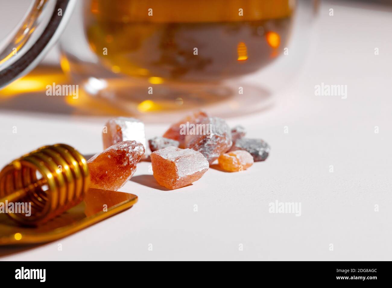 Brown sugar stones and honey dipper on white surface Stock Photo - Alamy