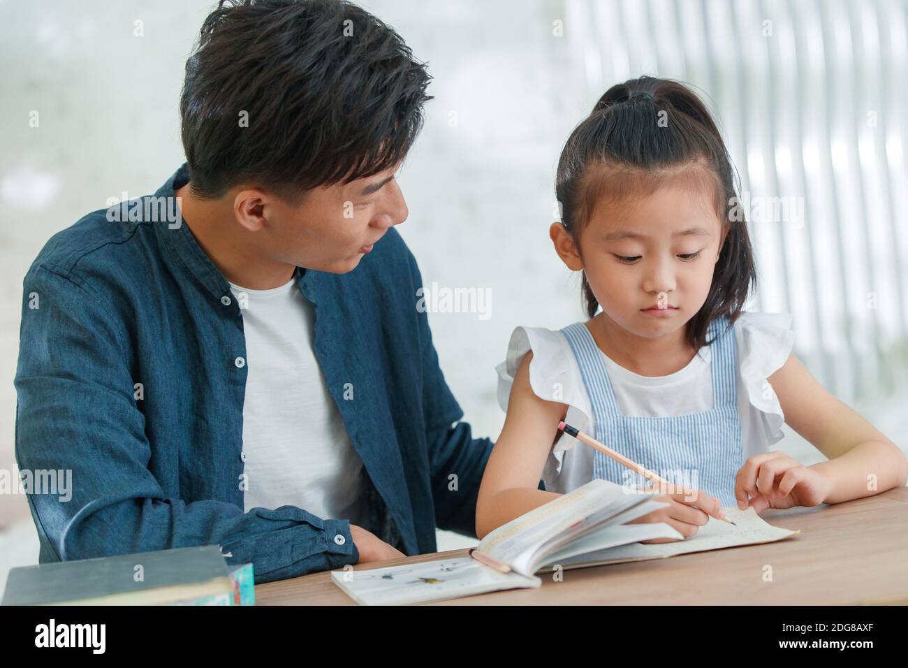 The young man to coaching daughter doing his homework Stock Photo - Alamy