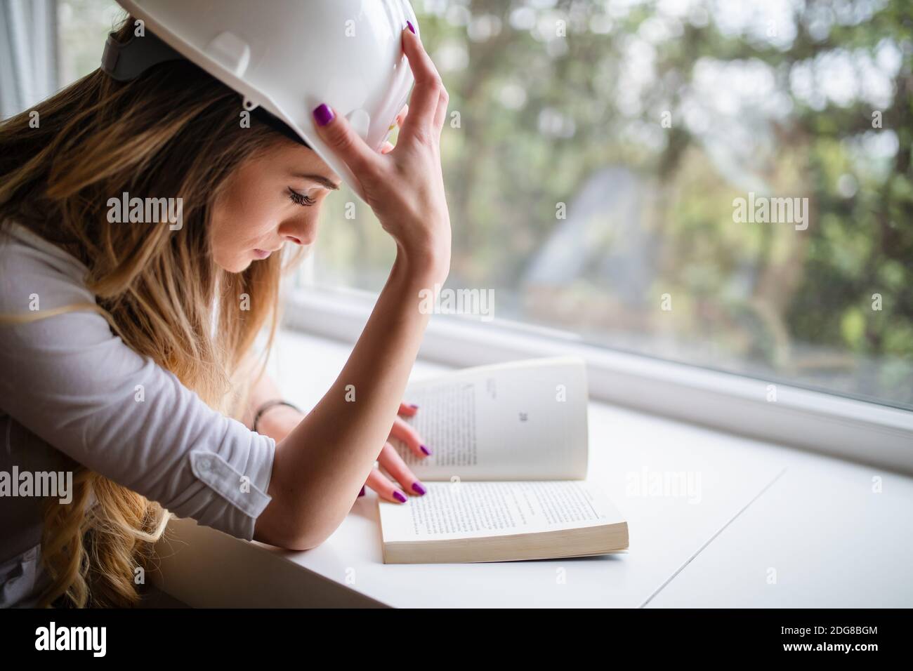 Teenage girl studying reading book at home concentrating looking down ...