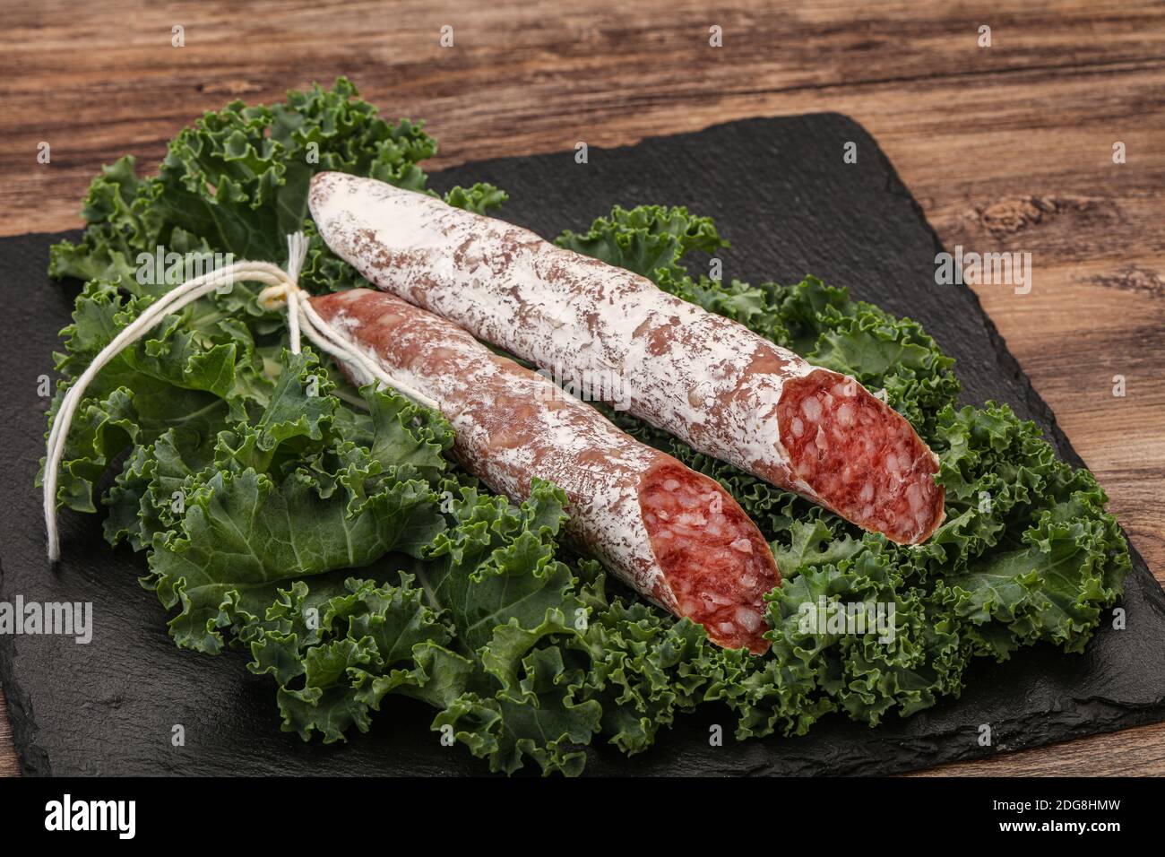 Spanish Fuet sausage with salad leaves over wooden background Stock ...