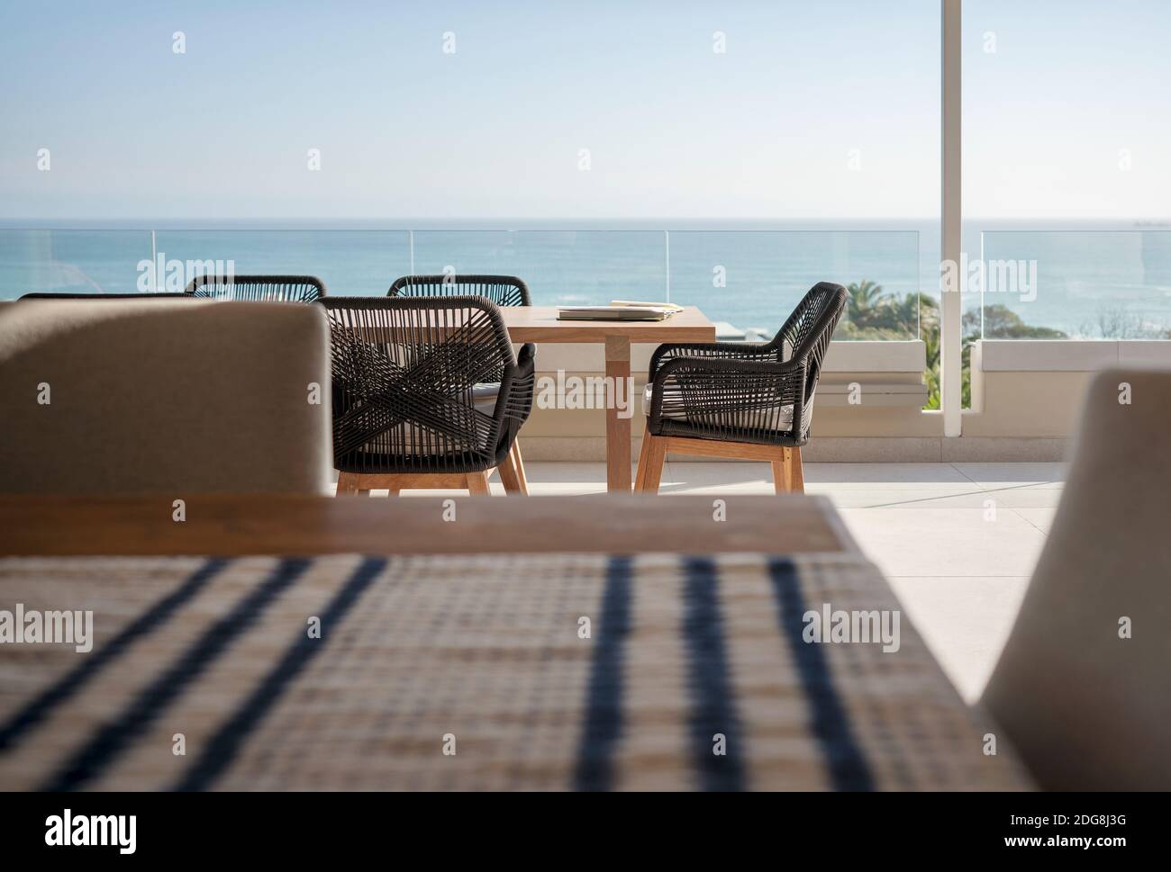 Ocean view behind dining table and chairs on sunny luxury patio Stock ...
