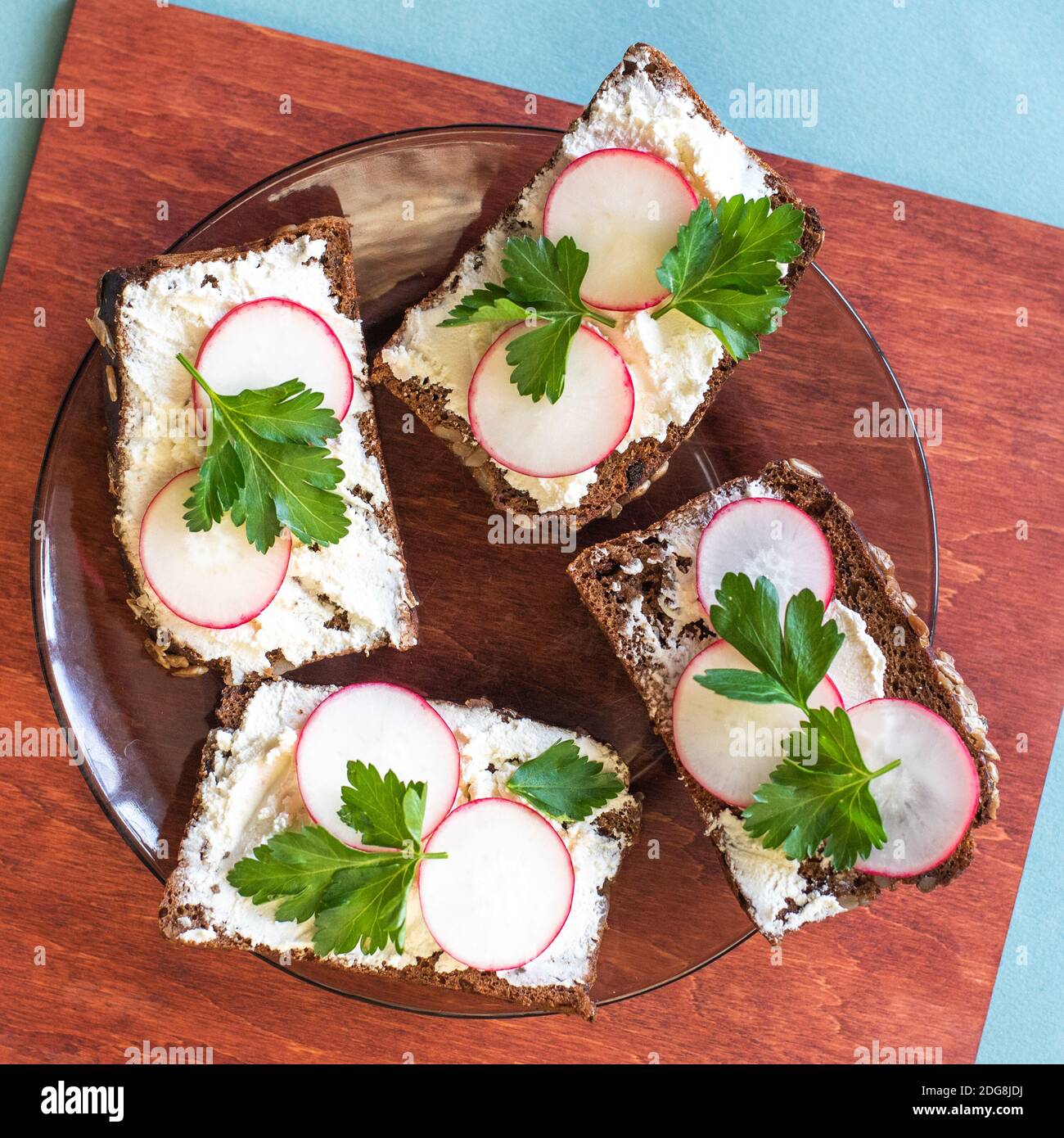 rectangular sandwiches with butter, cheese and radish on a black plate ...