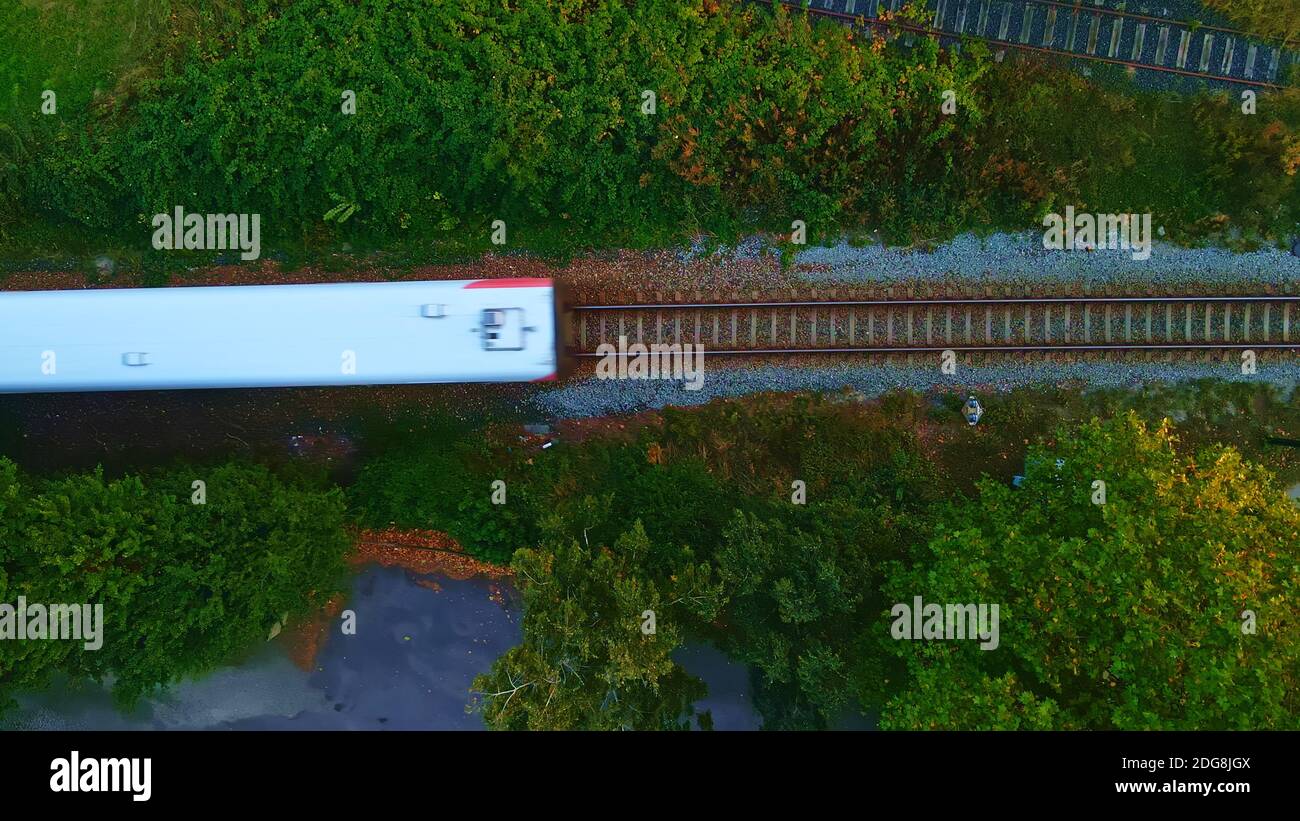 White passenger train passing by on railroad tracks. Aerial top down ...