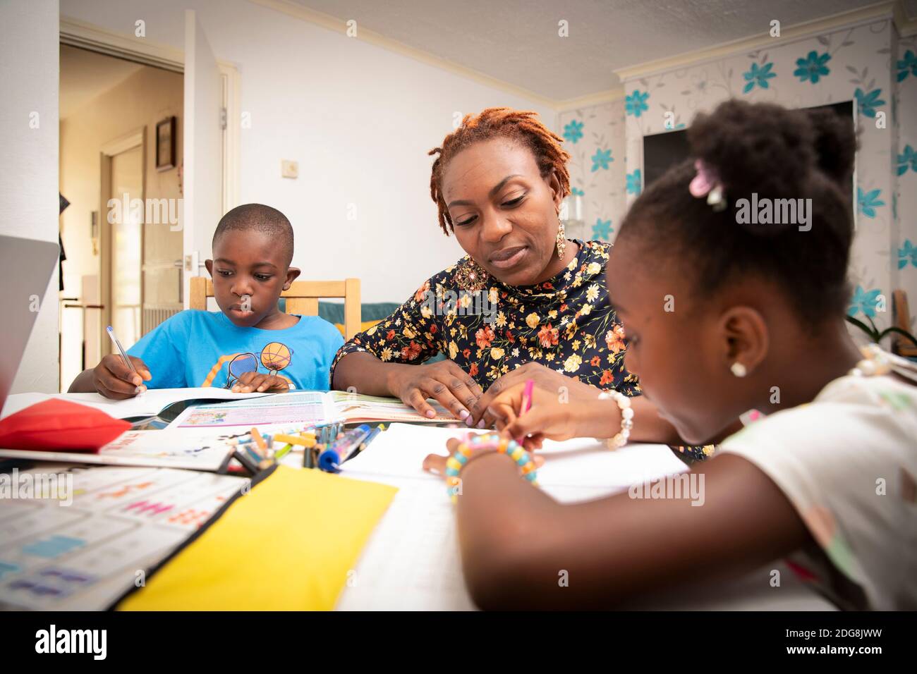 Mother helping kids with homework at dining table Stock Photo - Alamy