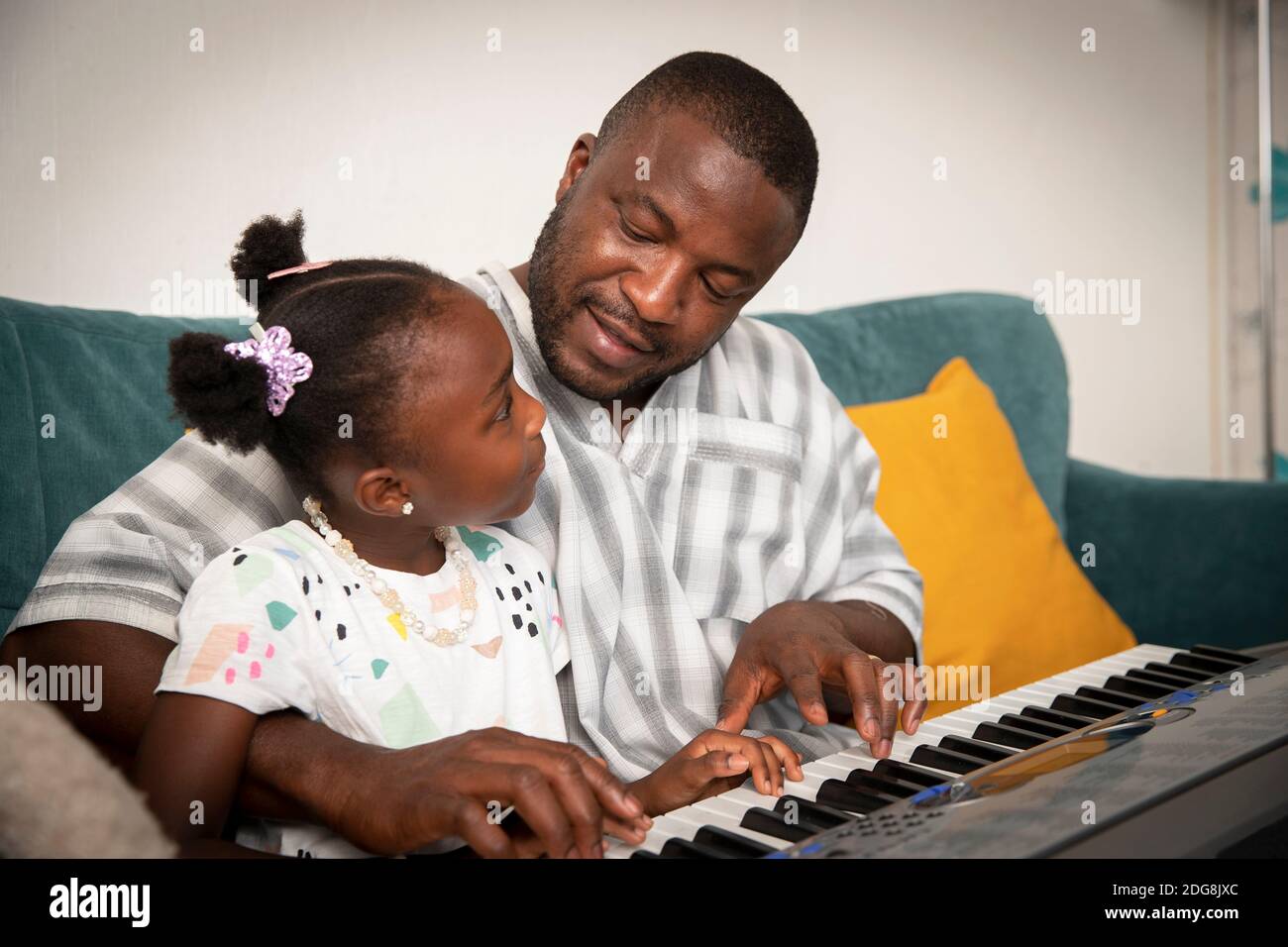 Affectionate father and daughter playing keyboard piano on sofa Stock ...